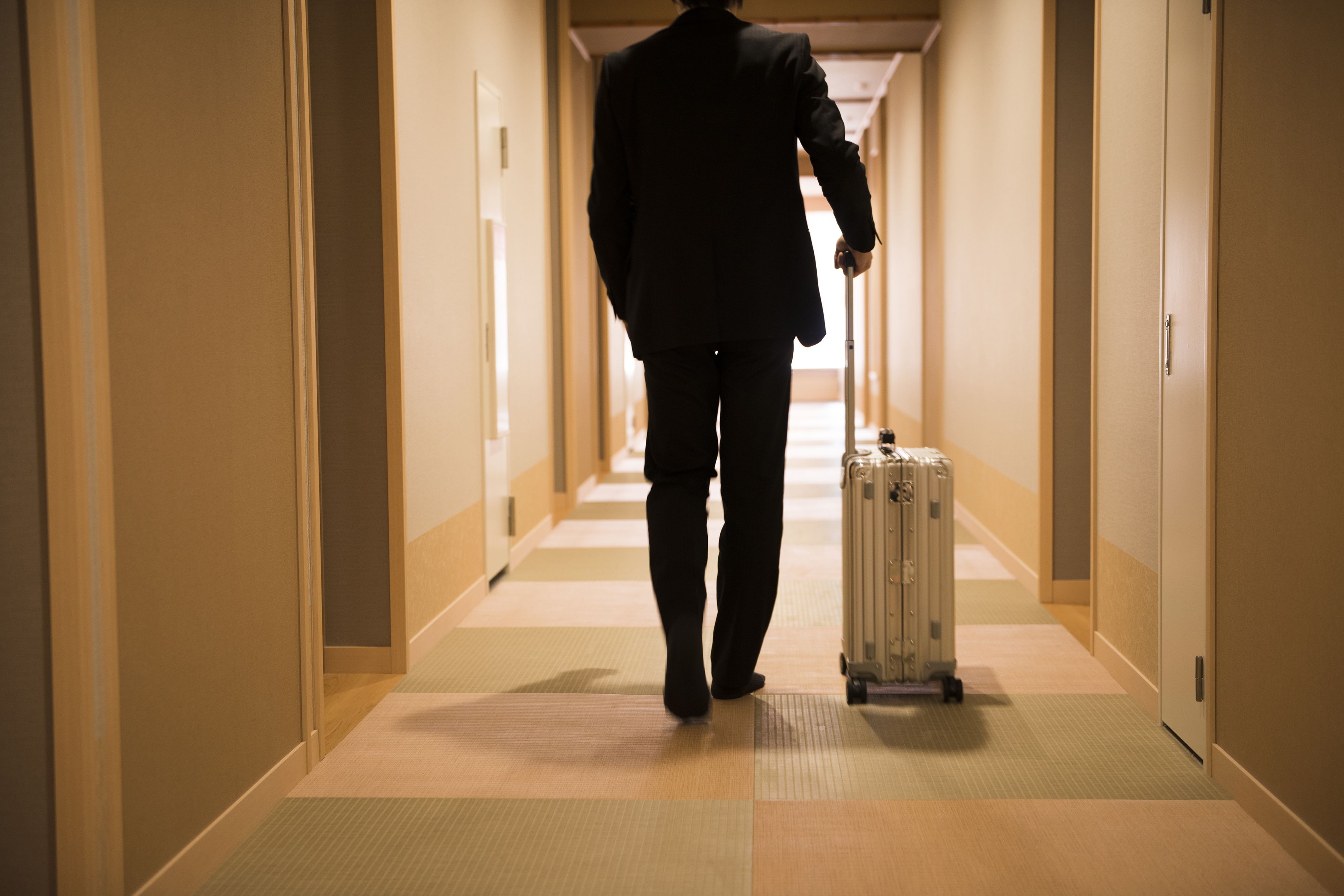 Um homem de terno caminhando por um corredor com uma mala.