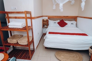 Um quarto com uma cama beliche de madeira, uma cama de solteiro com coberta xadrez vermelha e preta, e uma cesta de palha na prateleira.