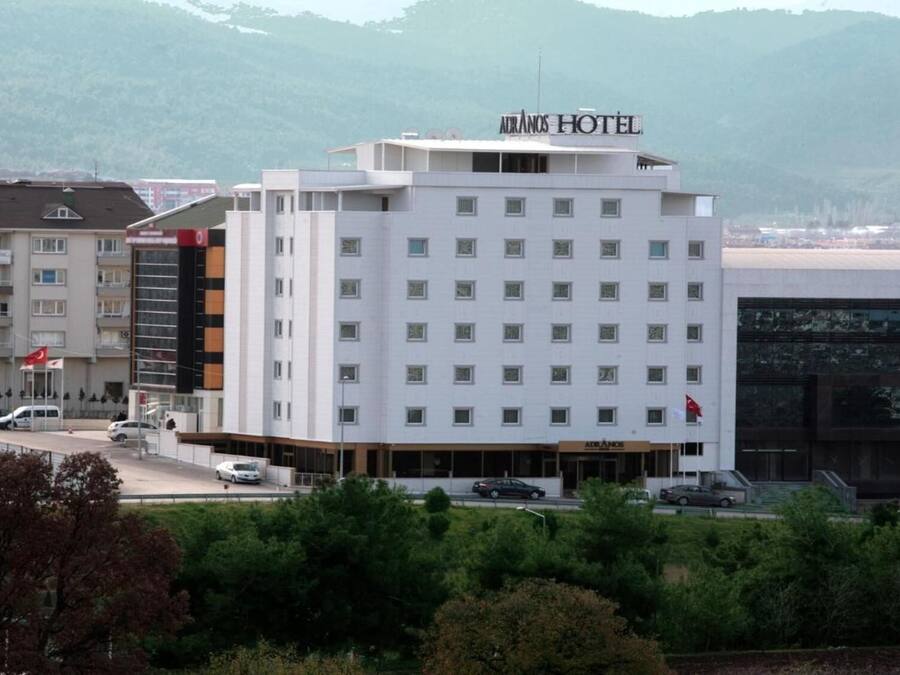 Um edifício de hotel com design moderno, vários andares e uma placa grande no topo.