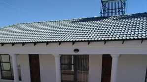 Um edifício com telhado telhado, colunas brancas e um espaço com pavimento de tijolos na frente.