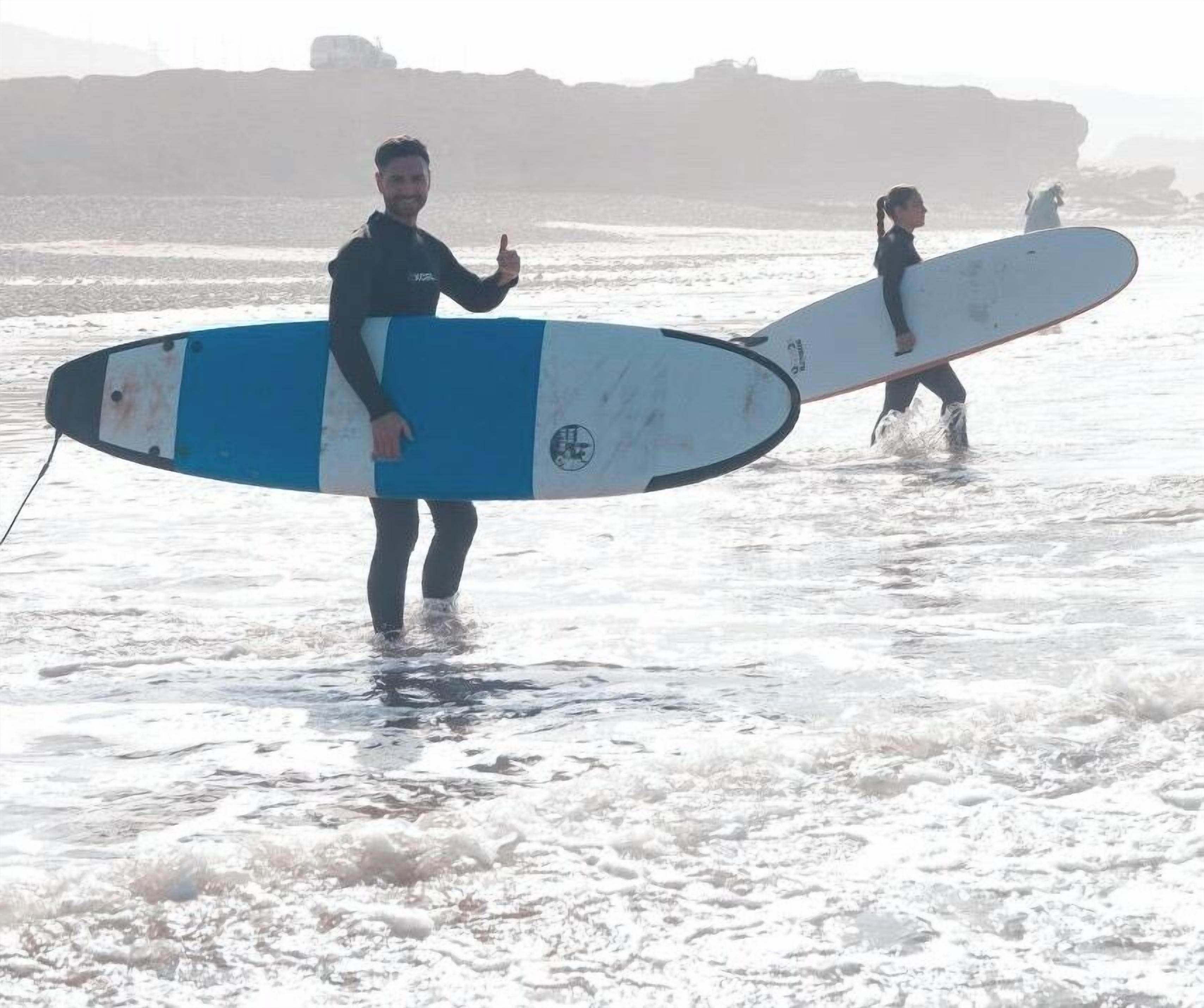 Uma pessoa segurando uma prancha de surf na praia.