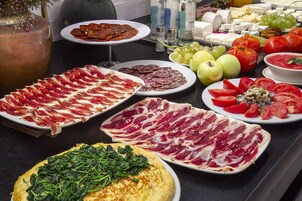 Buffet com diversos itens, incluindo carnes, queijos, frutas e vegetais.