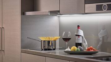 Uma cozinha moderna com eletrodomésticos de aço inoxidável, um prato de espaguete, uma taça de vinho e uma garrafa de vinho.