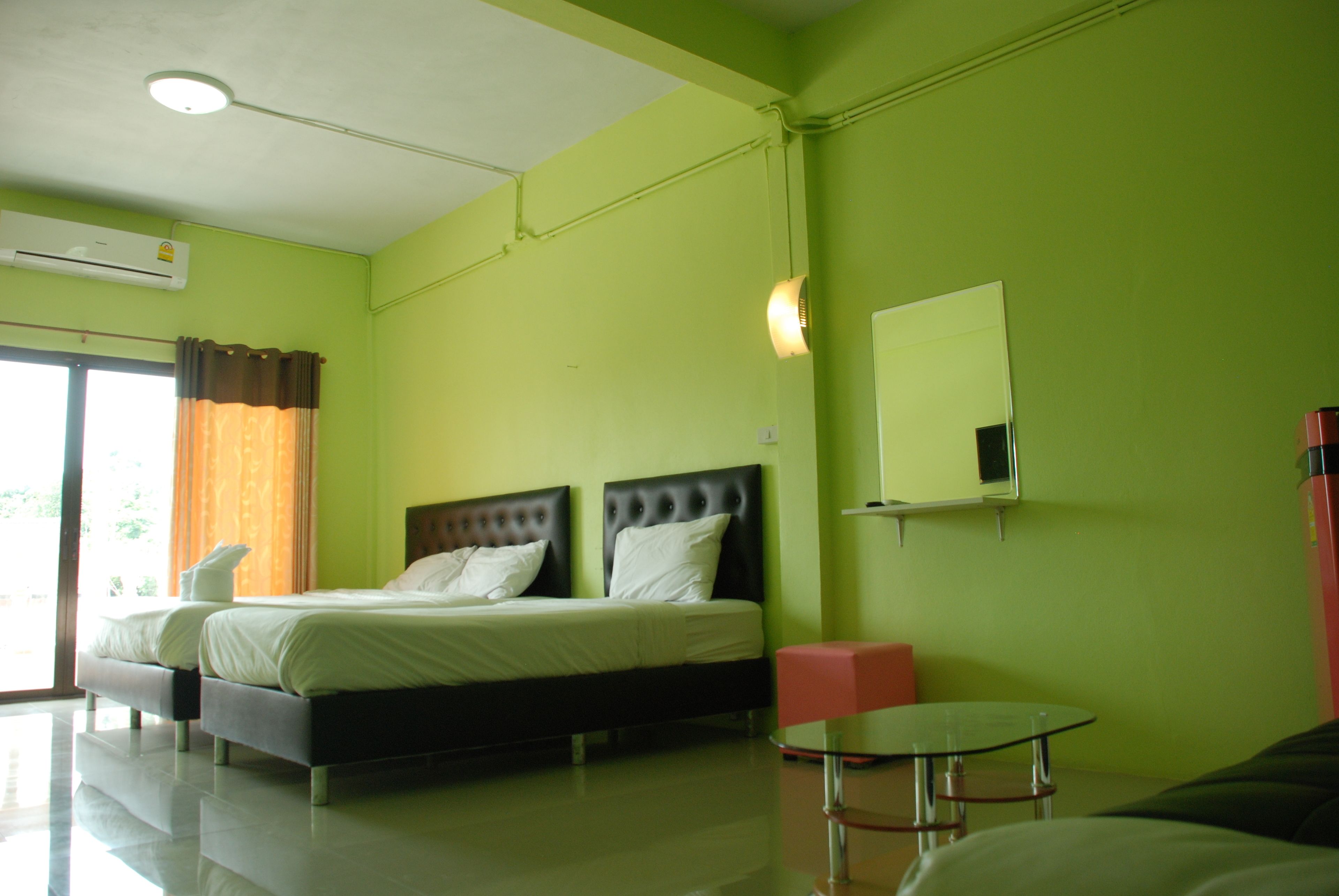 Quarto com duas camas, uma mesa de vidro e uma cadeira vermelha.