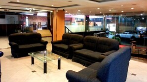Um hall com sofás, uma mesa de centro de vidro e um balcão de recepção.