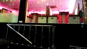 Um interior moderno com escada, divisórias de vidro e teto iluminado em rosa.