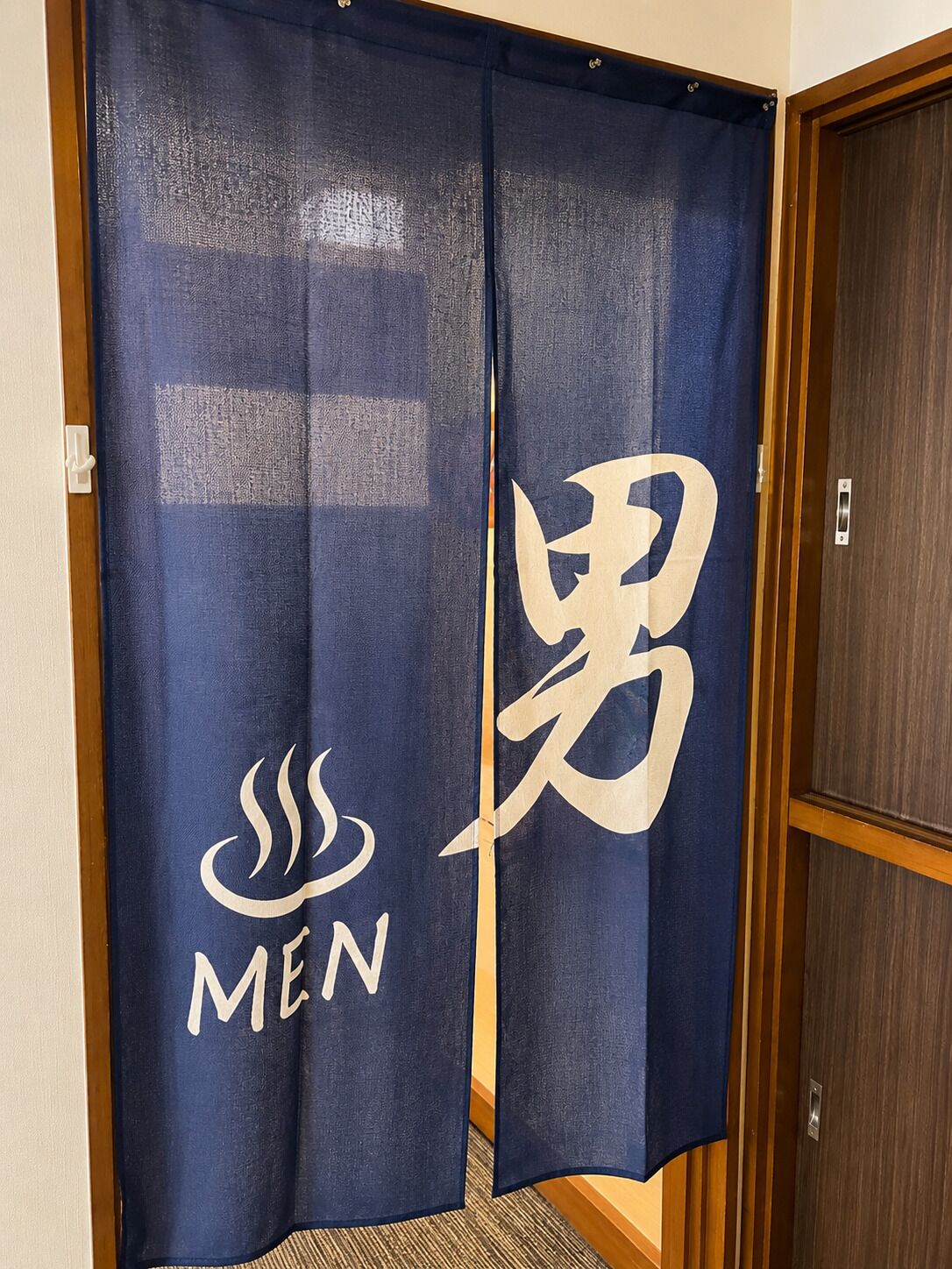 Quarto com cortina azul exibindo um logotipo e a palavra 'MEN'.