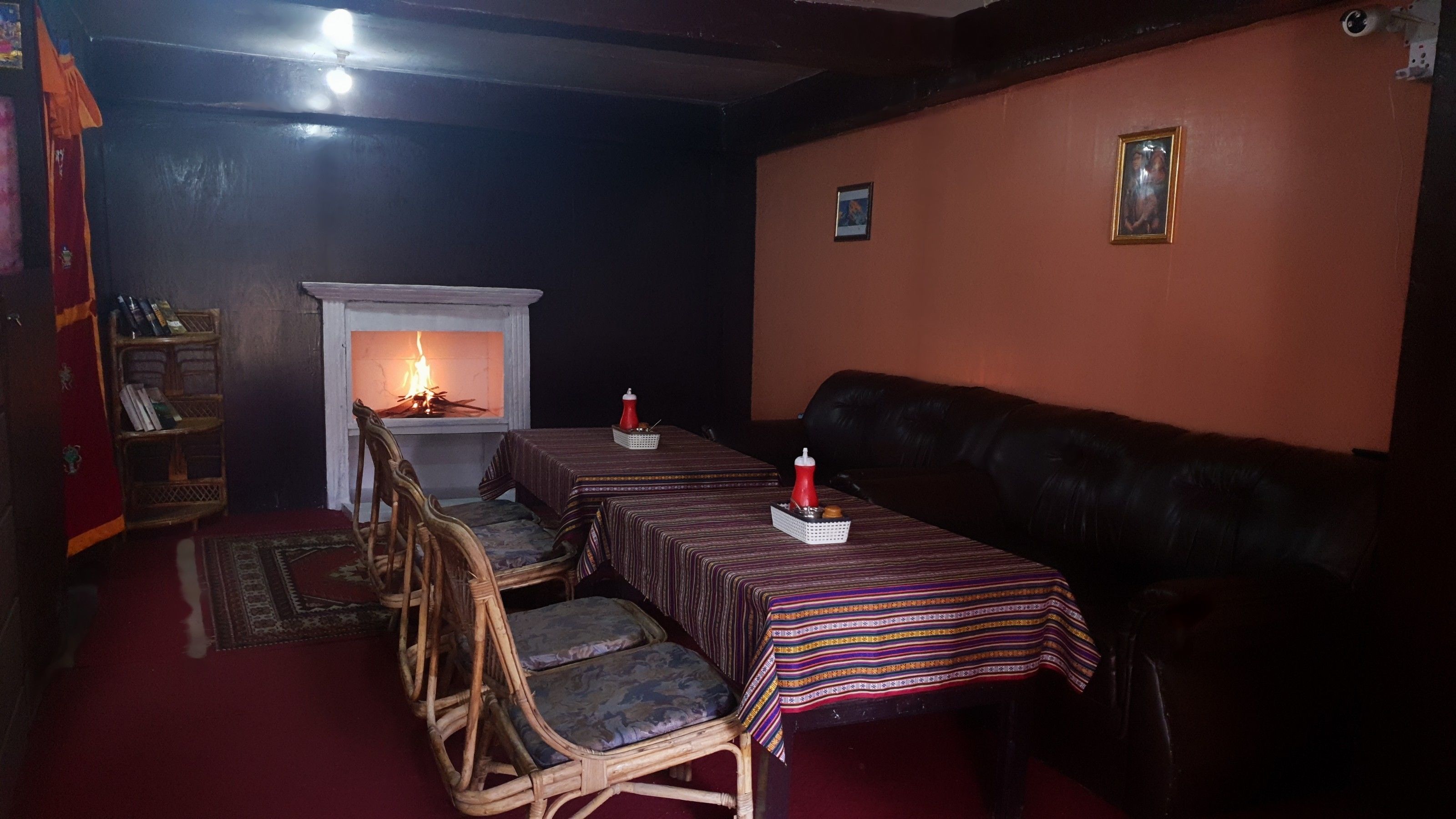 Um quarto aconchegante com lareira, um sofá, uma mesa de jantar com cadeiras e uma estante de livros.