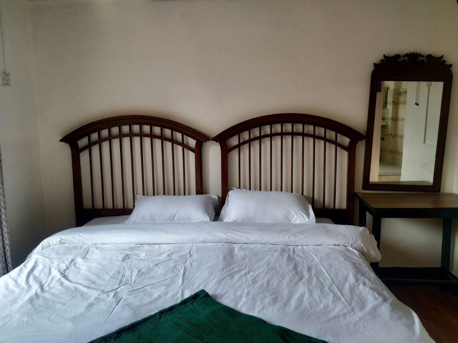 Uma cama de casal com cabeceira de madeira, uma mesa de cabeceira e um espelho.