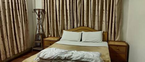 Quarto com uma cama, duas mesas de cabeceira, um criado-mudo e uma cadeira de madeira.