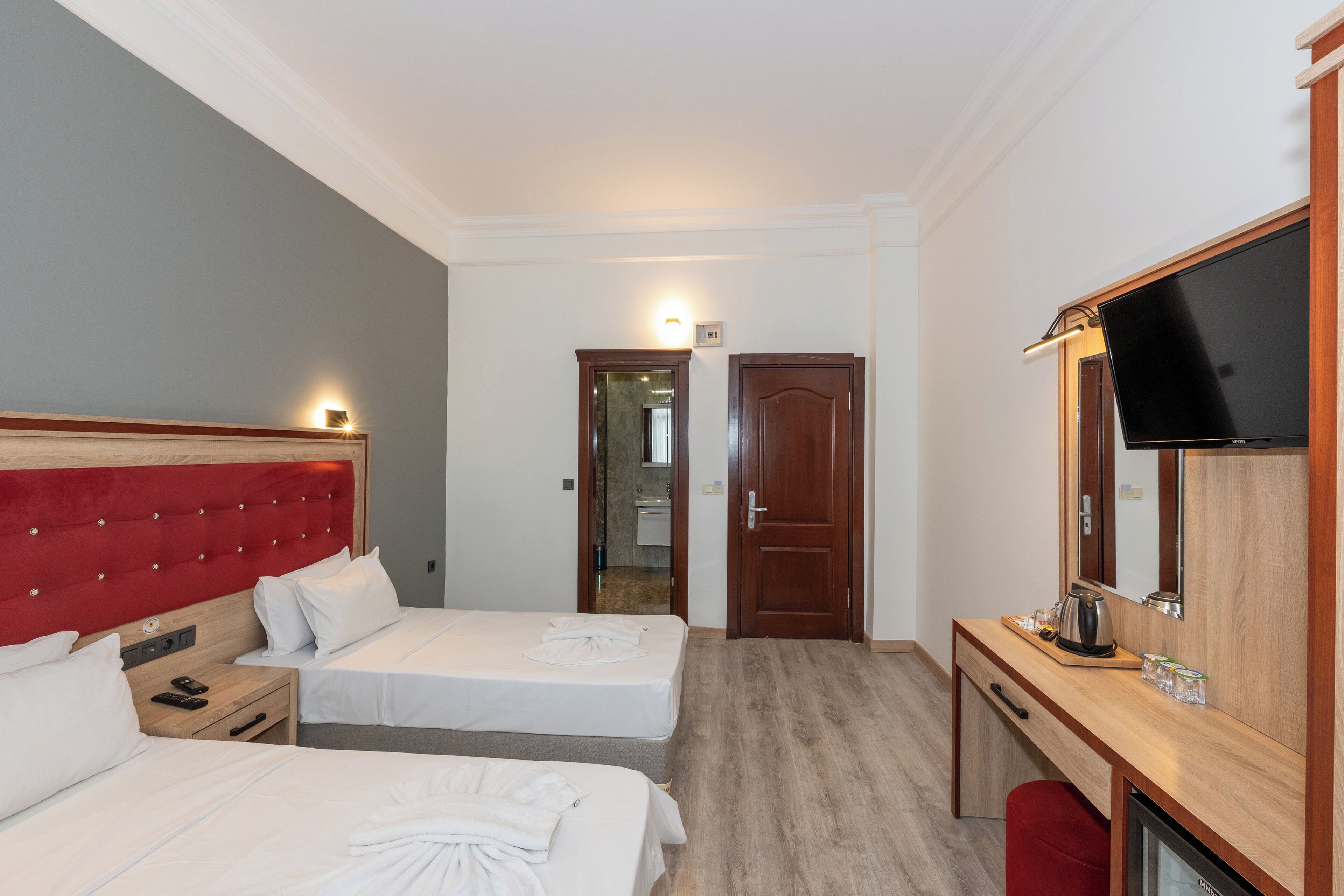Quarto de hotel com duas camas, uma mesa de trabalho e um espelho.