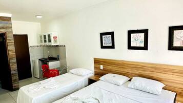 Quarto de hotel com duas camas, uma kitchenette e um banheiro.