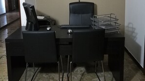 Um espaço de escritório moderno com uma mesa, duas cadeiras, um computador e um relógio de parede.