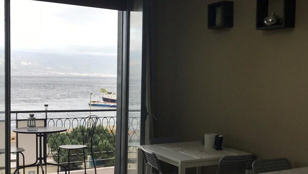 Uma varanda com mesa e cadeiras, com vista para um corpo d'água e barcos.