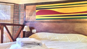 Um quarto acolhedor com cama, teto de madeira, parede de tijolos e uma pintura abstrata colorida.
