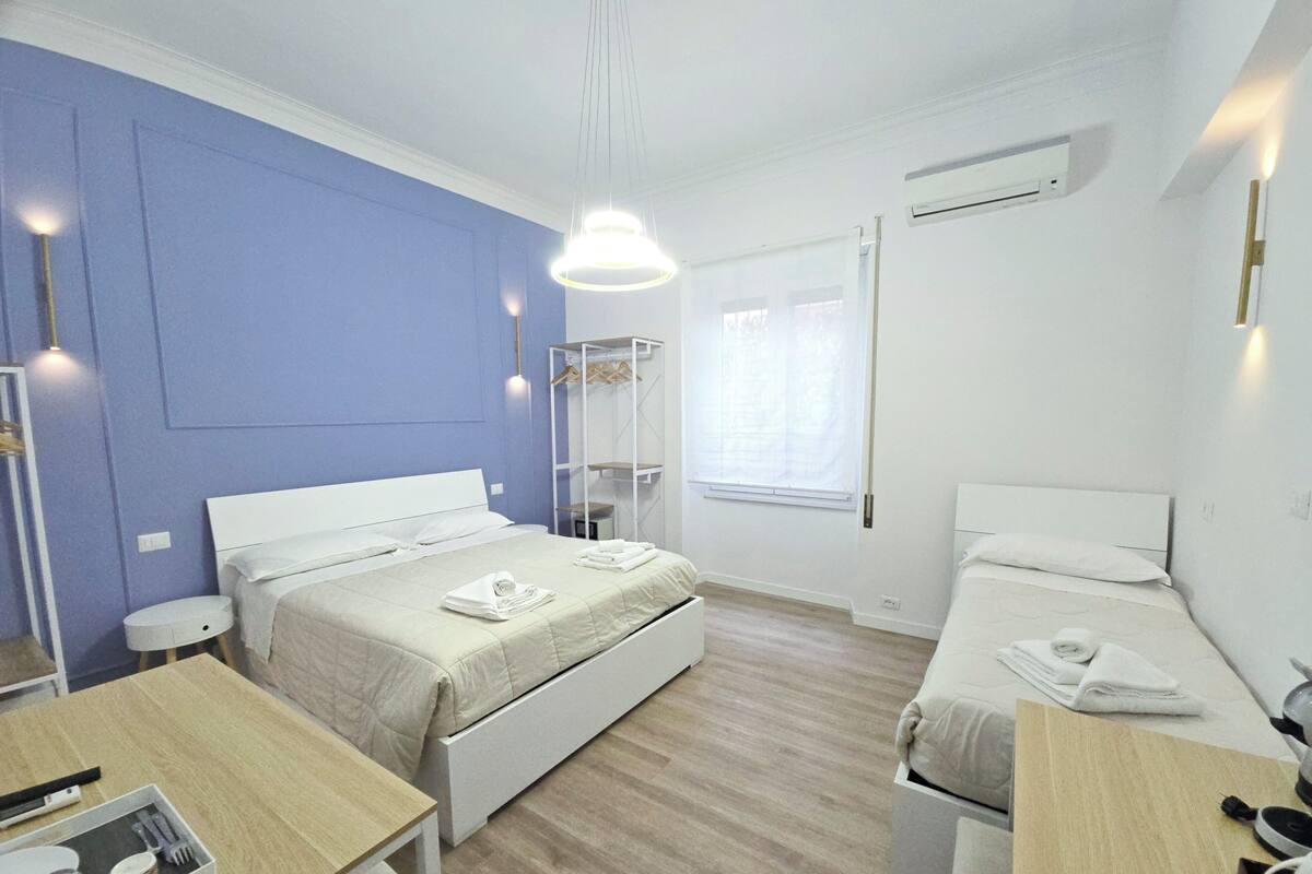 Um quarto moderno com uma cama grande, uma cama menor, uma escrivaninha e um guarda-roupa.