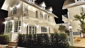 Uma casa grande e com vários andares, com varanda e fachada bem iluminada.
