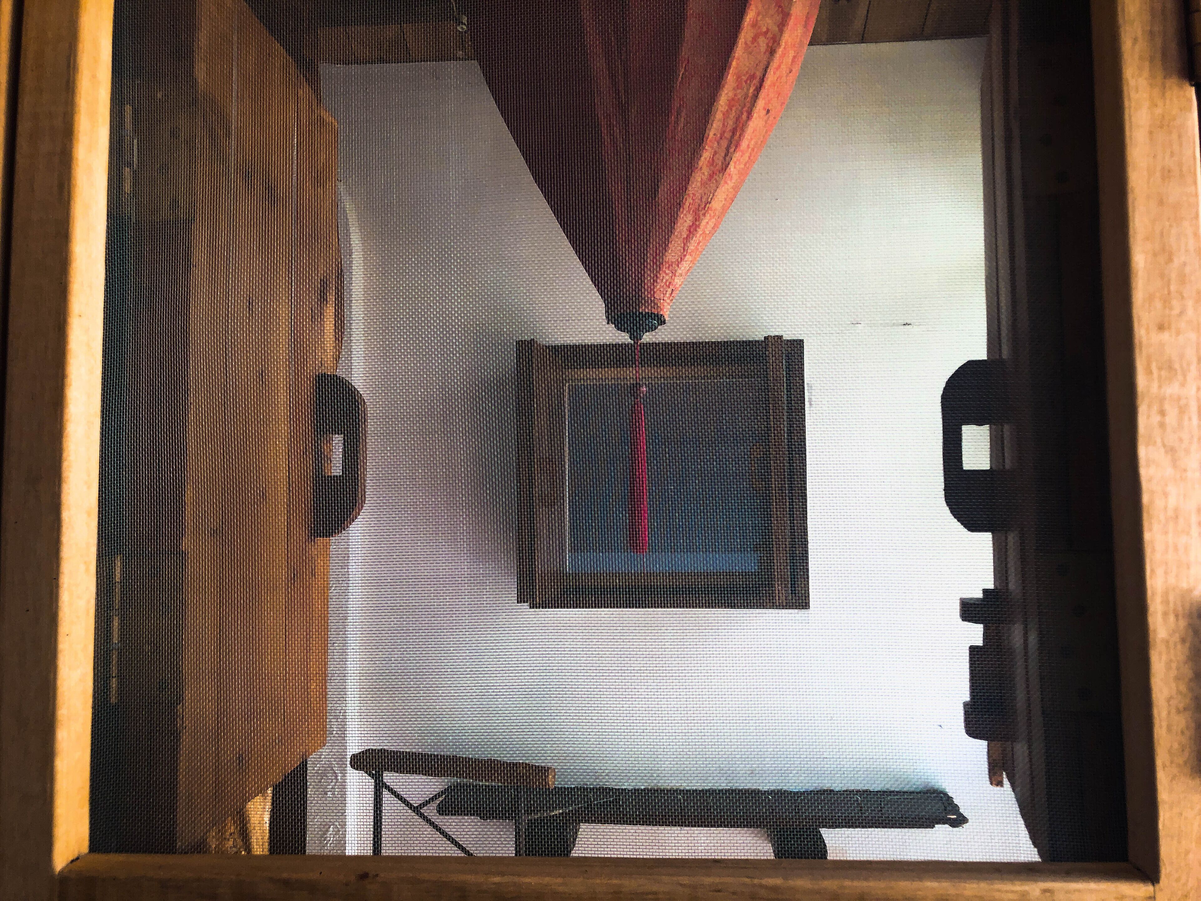 Quarto com uma grande janela, uma cama e cabeceira de madeira.
