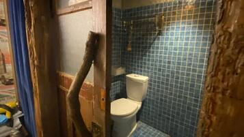 Casa de banho com chão e paredes azulejadas em azul, sanita branca e candeeiro suspenso.