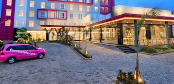 Um hotel com design moderno, apresentando uma entrada imponente com área coberta e interior luminoso.