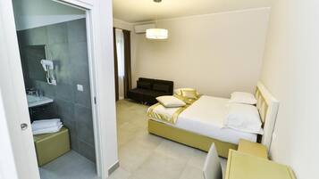 Quarto de hotel moderno com uma cama grande, mesa de cabeceira, escrivaninha e área de chuveiro.