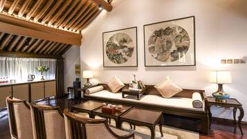 Uma sala de estar em estilo tradicional, com um sofá, cadeiras, uma mesa de centro e obras de arte nas paredes.