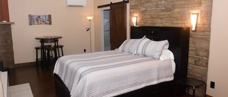 Quarto com cama, uma mesinha e uma cadeira.