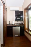 Uma cozinha compacta com micro-ondas integrado, lava-louças e uma janela com persianas.