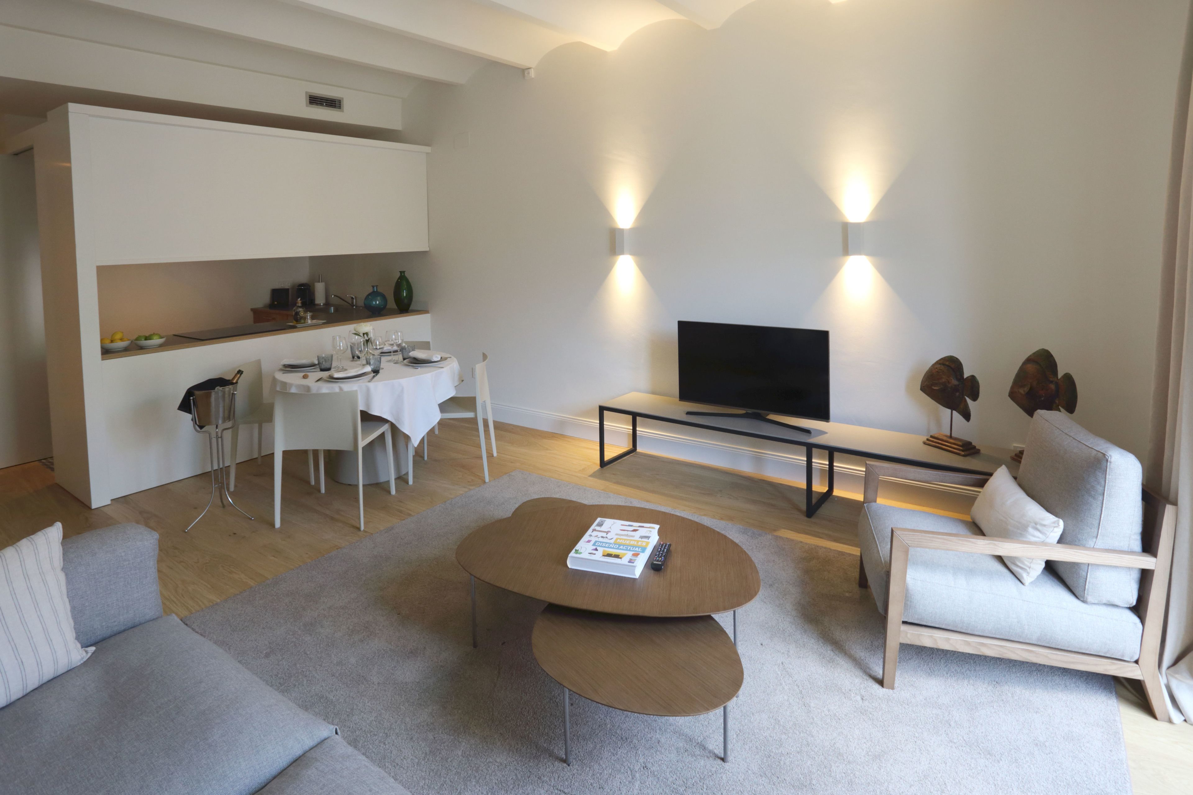 Uma sala de estar moderna com sofá, mesa de centro, televisão e um espaço de jantar com mesa e cadeiras.