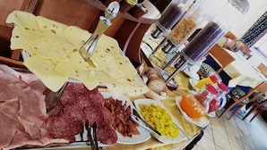 Uma mesa de buffet com diversos tipos de comida, incluindo carnes, queijos e frutas.