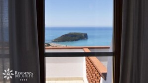 Vista da janela de um edifício com vista para uma área costeira, uma pequena ilha e uma praia.