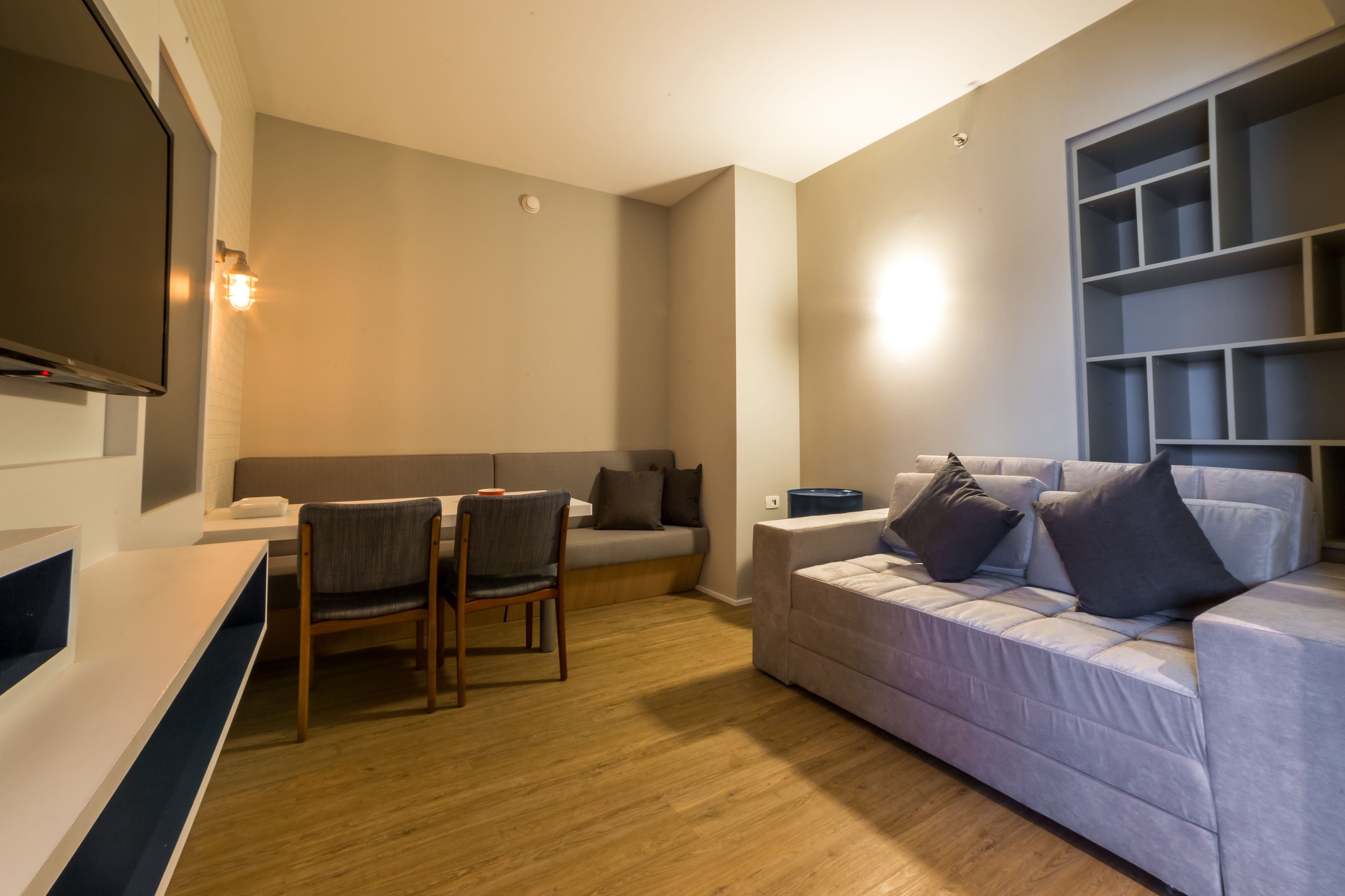 Uma sala de estar moderna com sofá, poltronas, televisão e estantes embutidas.