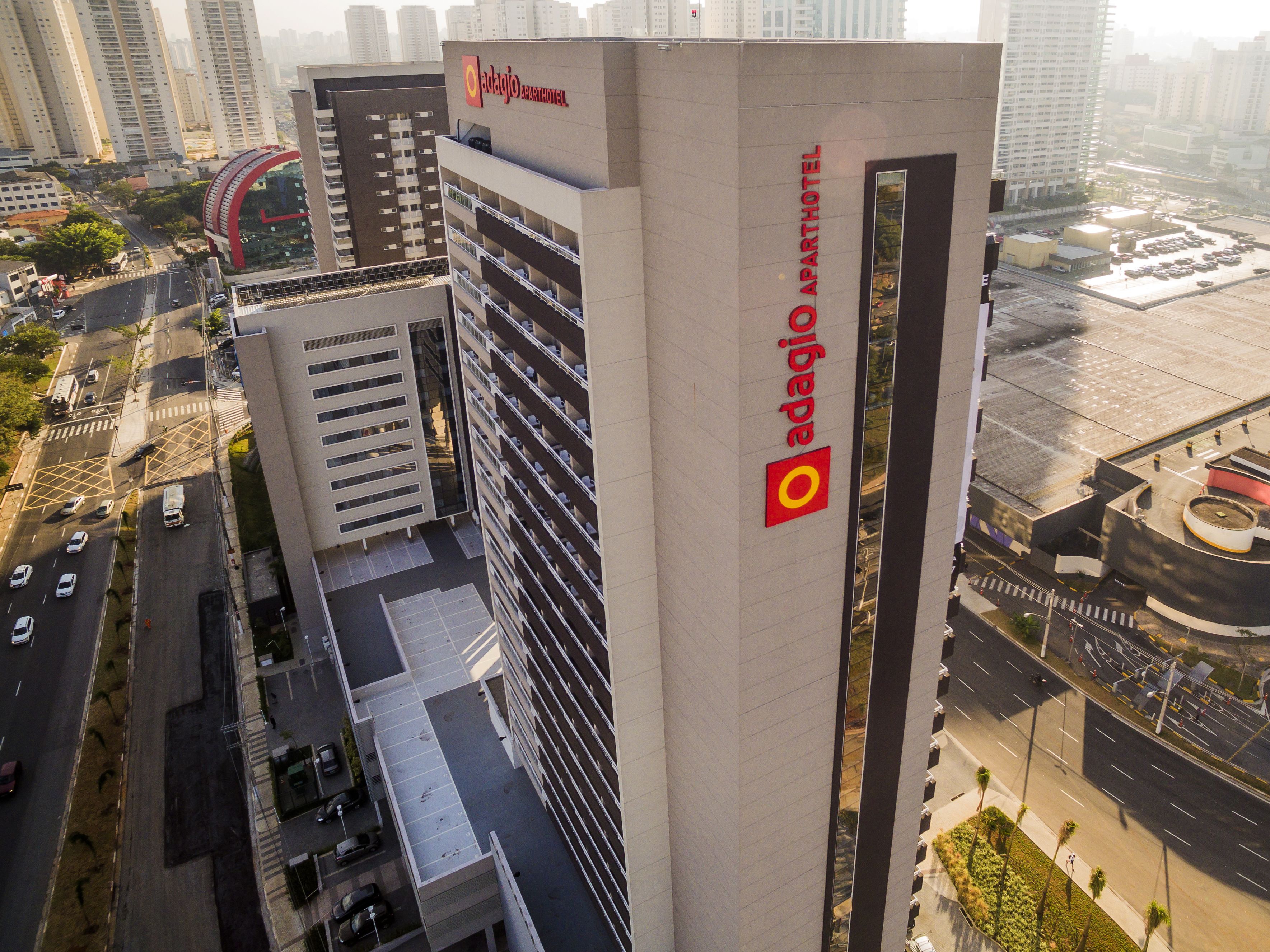 Um edifício moderno de vários andares com uma placa de destaque para 'Adagio Apart Hotel'.