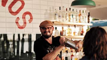 Um bartender prepara uma bebida atrás de um balcão com prateleiras cheias de garrafas.