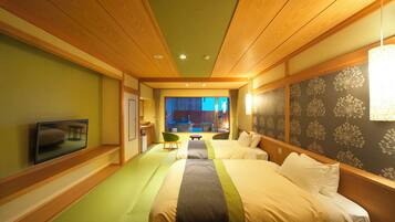 Quarto de hotel com duas camas, televisão, uma mesinha e vista para o exterior.