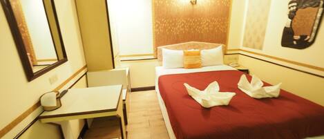 Quarto de hotel com uma cama, escrivaninha, cadeira, espelho e ar condicionado fixado na parede.