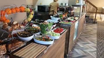 Buffet com diversas opções de comida, incluindo frutas, vegetais e pão.