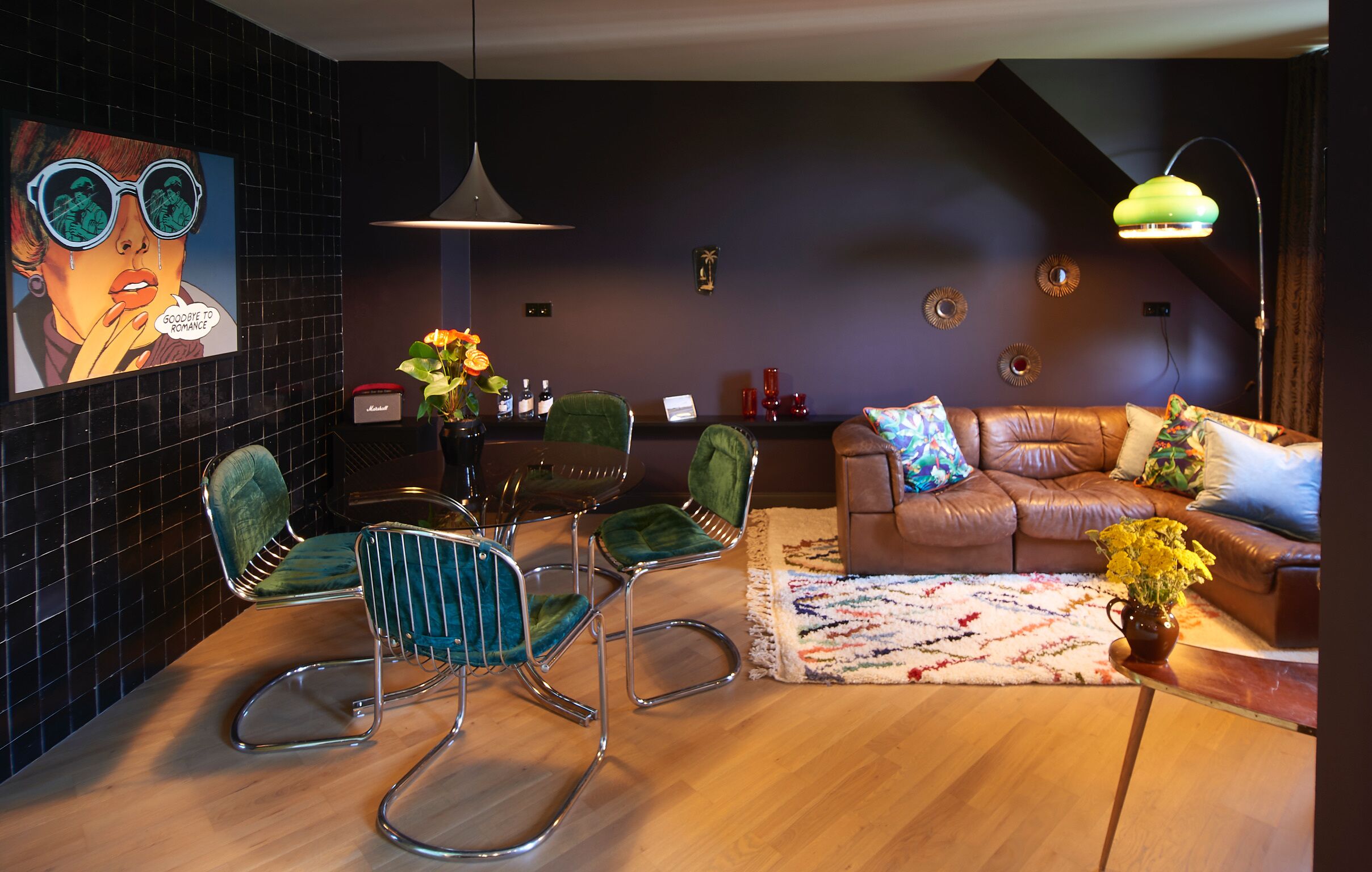 Uma sala de estar moderna com um sofá de couro marrom, cadeiras verdes, uma mesa de centro e um tapete.