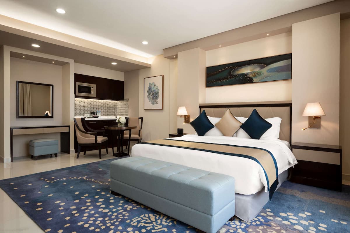 Quarto de hotel moderno com uma cama grande, uma escrivaninha e um espaço de estar.