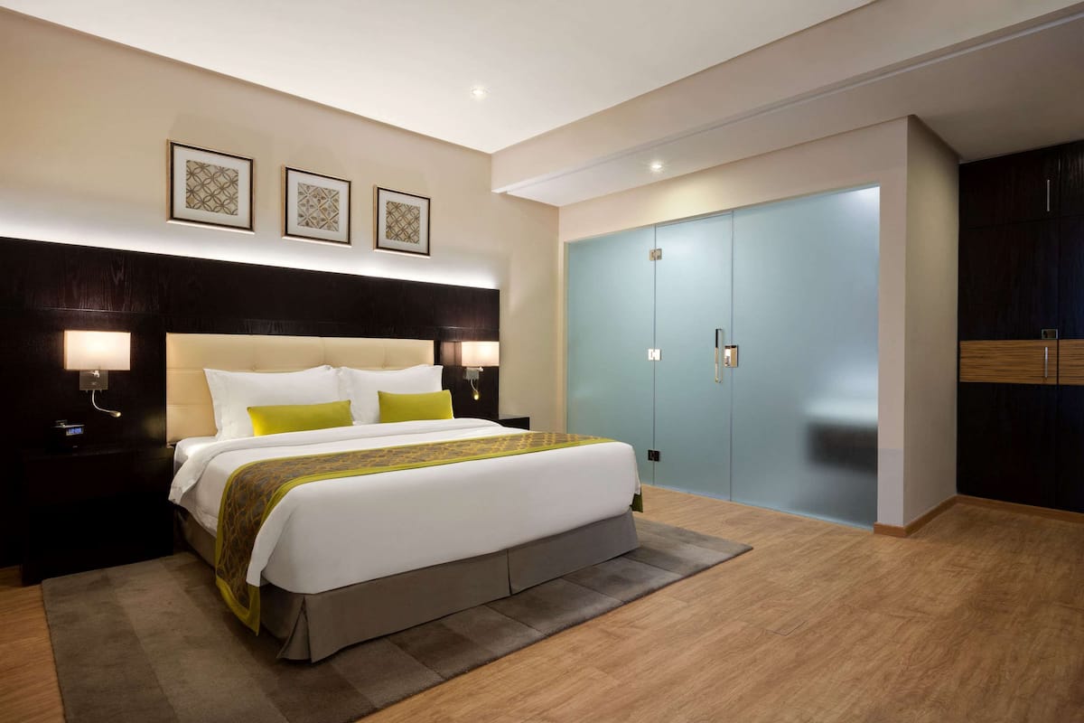 Quarto moderno com cama grande, mesas de cabeceira, guarda-roupa e quadros na parede.