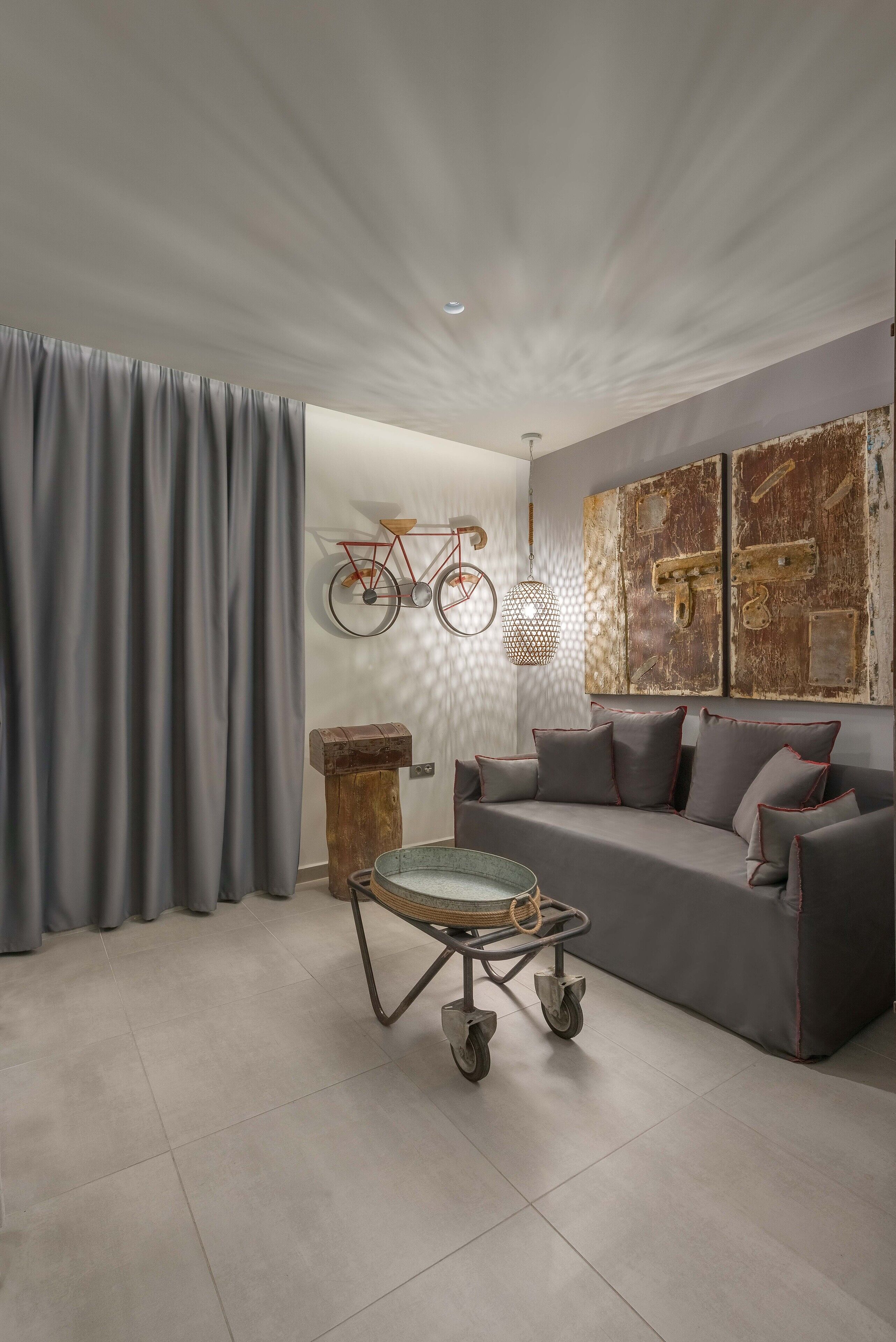 Uma sala de estar moderna com um sofá cinzento, um banquinho de madeira e um carrinho de metal.