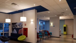 Uma área de estar moderna, com assentos, uma janela grande e uma placa com a palavra 'Lounge'.