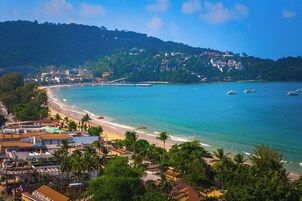 Uma vila costeira com praia, barcos e edifícios numa encosta.