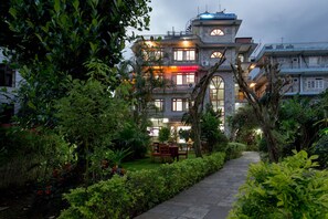 Um hotel com caminho no jardim, área de estar externa e fachada bem iluminada.