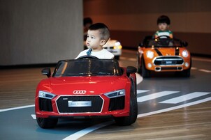 Uma criança dirigindo um carrinho de brinquedo em um tapete de atividades.