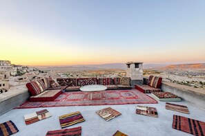 Terraço no telhado com sofás, uma mesa redonda e vista para a paisagem urbana.
