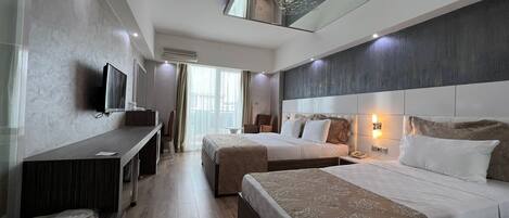 Quarto de hotel com cama, escrivaninha, cadeira, televisão e janela.