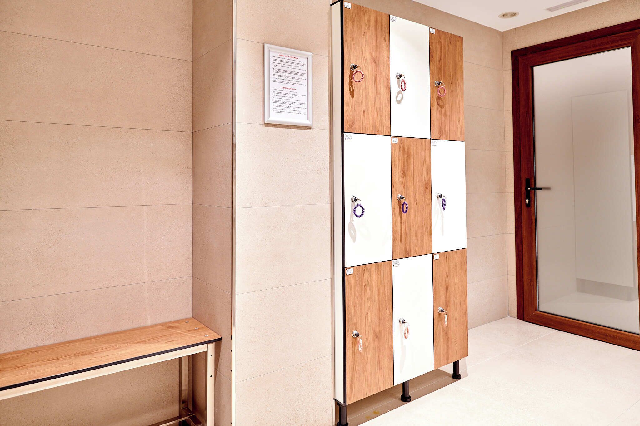 Um corredor com um banco, um armário de madeira com vários compartimentos e uma porta.