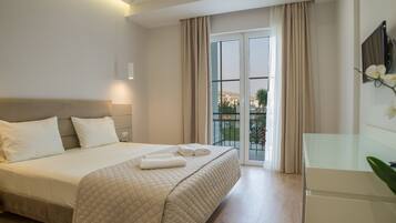 Quarto de hotel com cama, escrivaninha e vista para o exterior através de uma porta de correr.