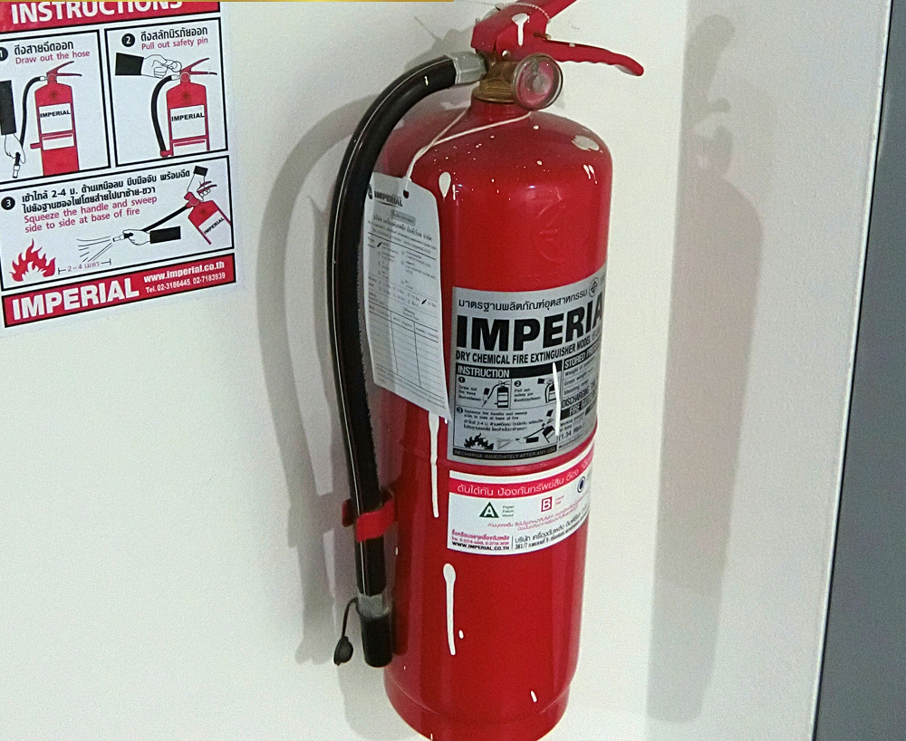 Um extintor de incêndio vermelho fixado na parede, com instruções e informações de segurança.